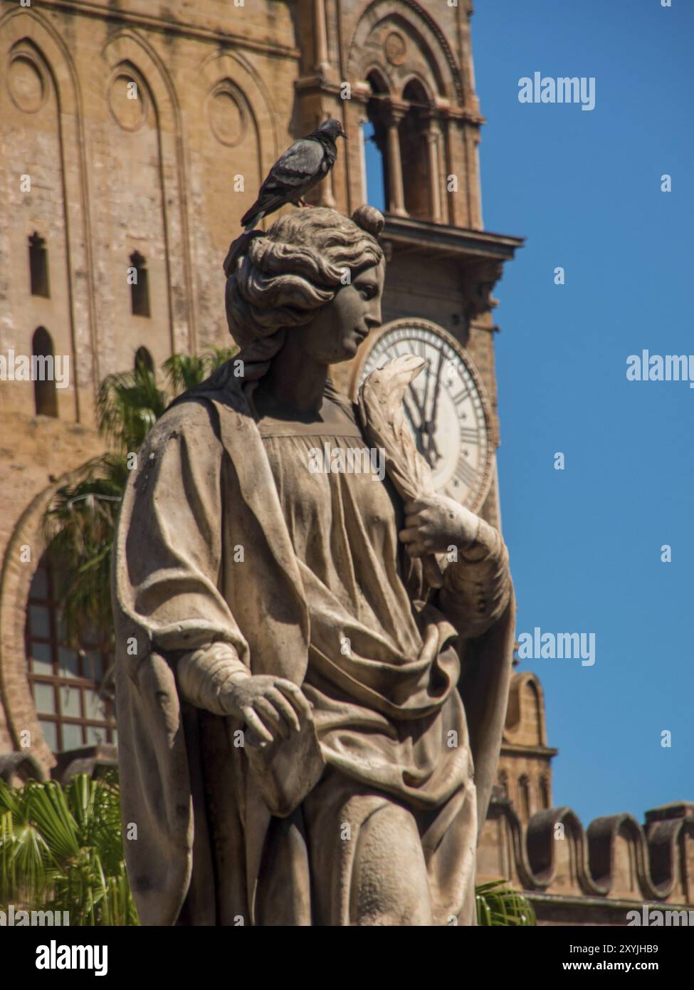 Close-up of a statue in front of the clock tower of a gothic cathedral ...
