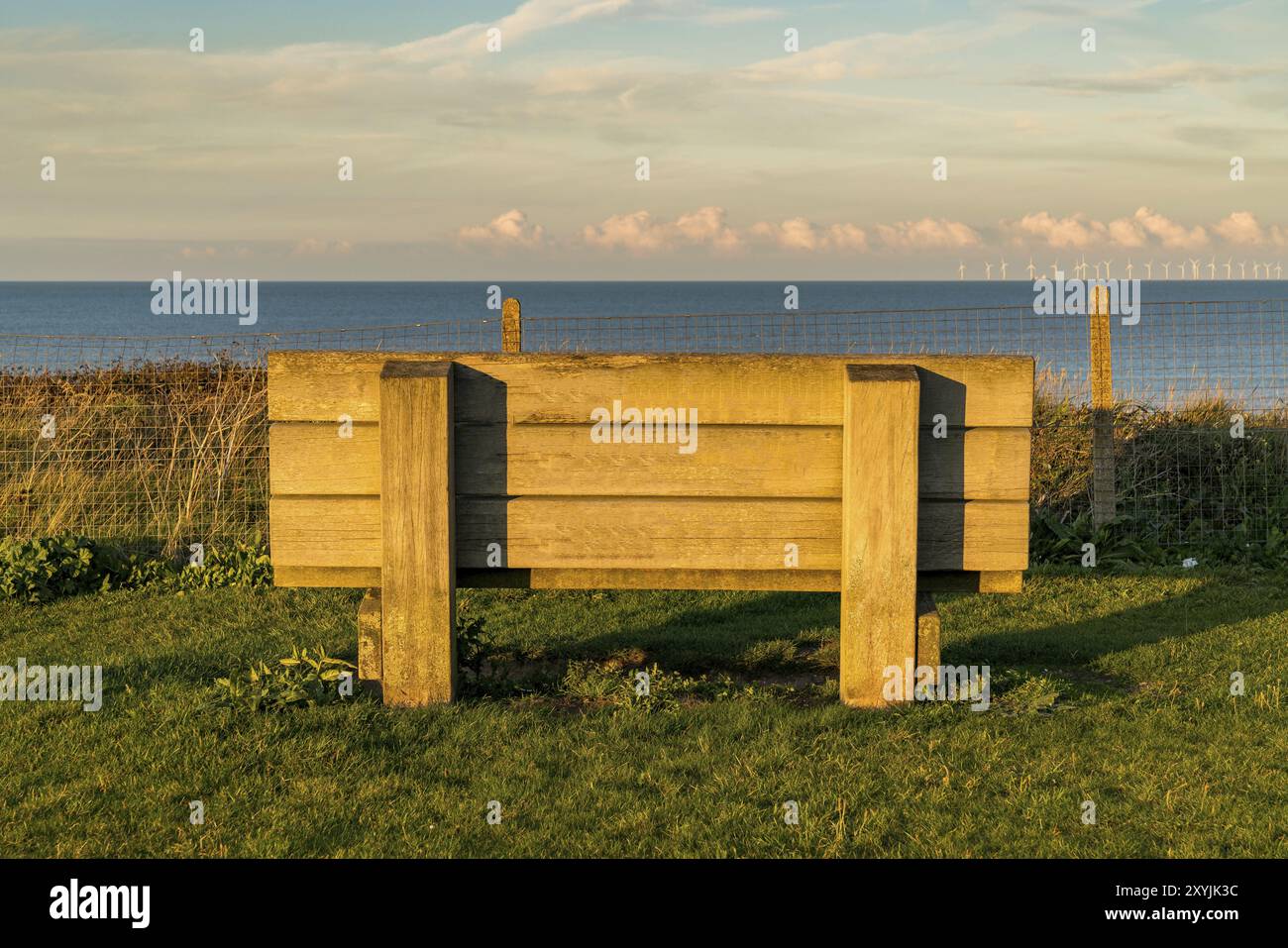 A large bench with a view over the North Sea and some wind turbines ...