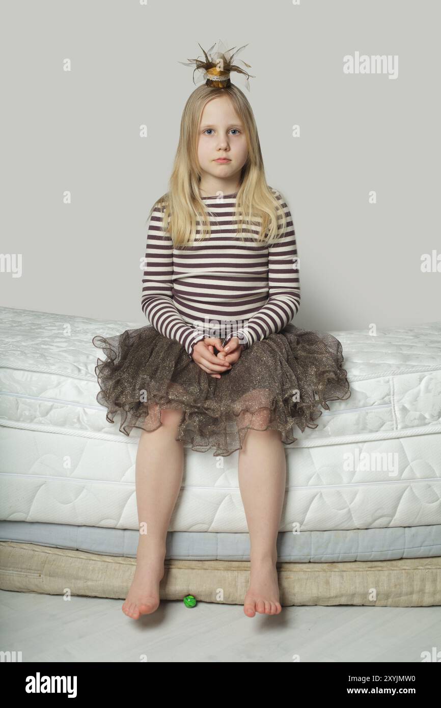 Princess and the pea concept. Beautiful child girl sitting on big ...