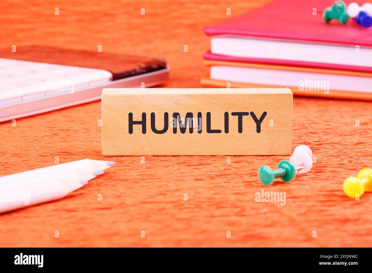 Lifestyle concept. HUMILITY word on a wooden bar in front of an orange ...