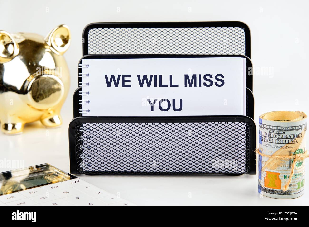 WE WILL MISS YOU written in a notebook in a stand on a white background ...