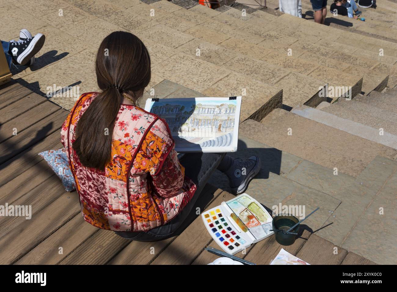 Woman painting with watercolours on the steps of a Roman theatre ...