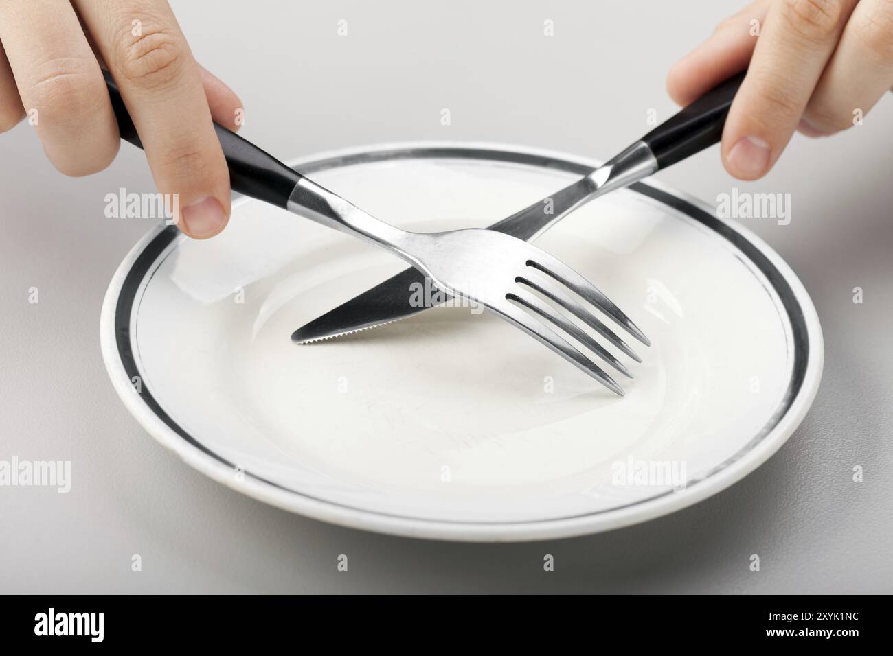 Hungry person hand holding fork knife on food plate Stock Photo - Alamy