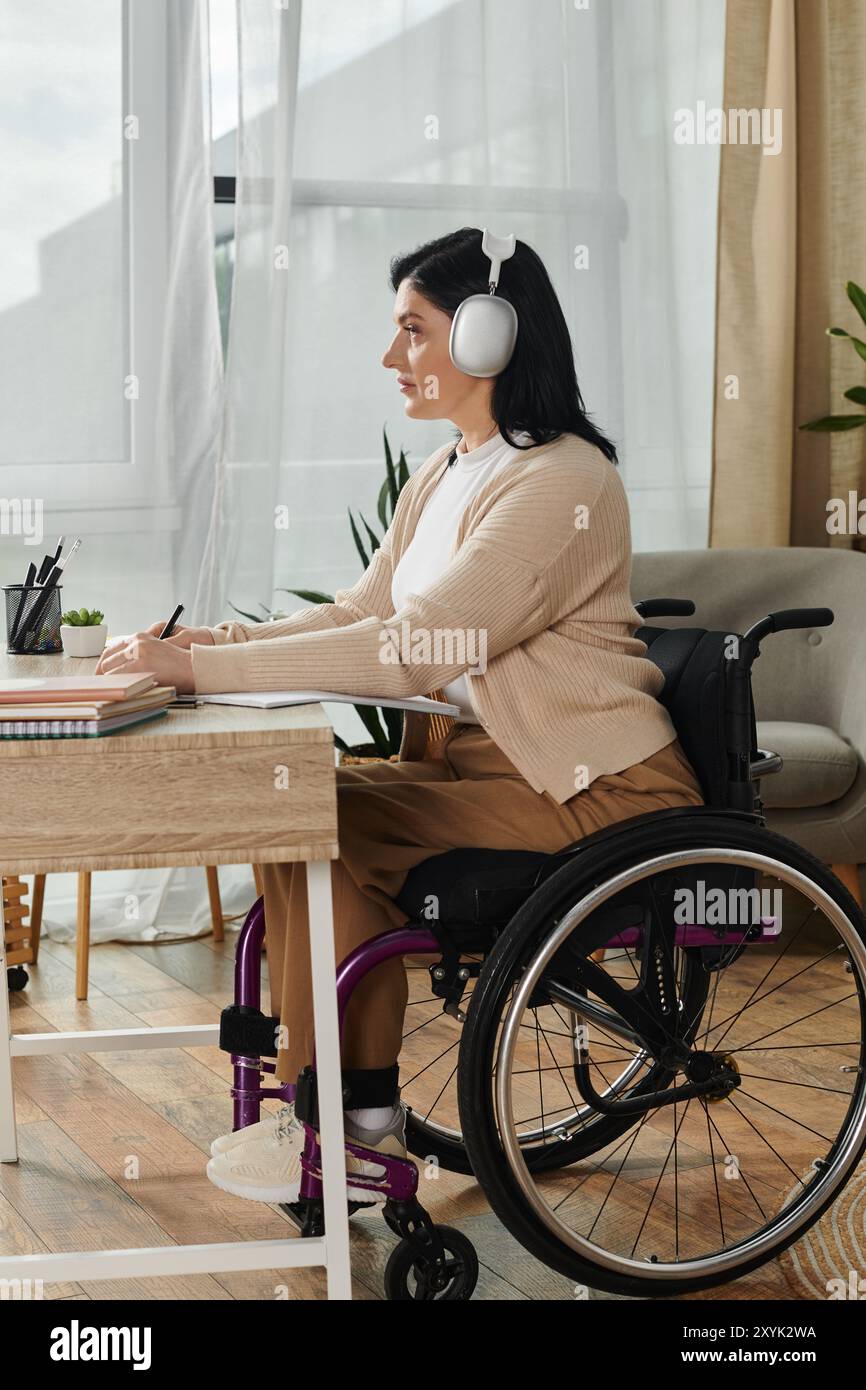 A woman in a wheelchair sits at a desk, headphones on, working intently ...