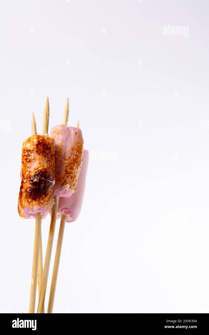 A vertical photo featuring skewers with perfectly toasted marshmallows ...