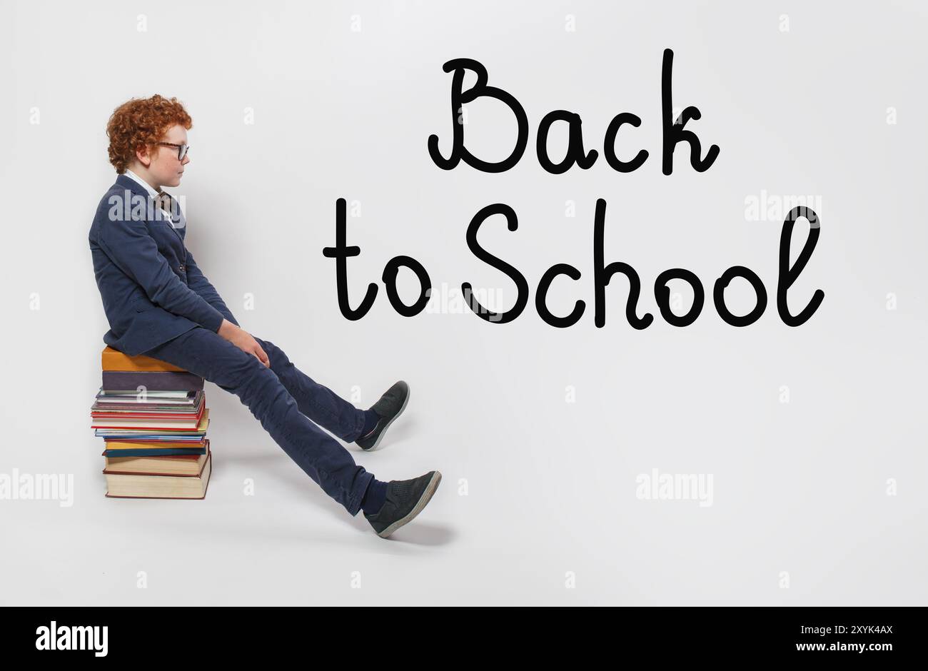 Clever school kid with books against white studio wall background ...