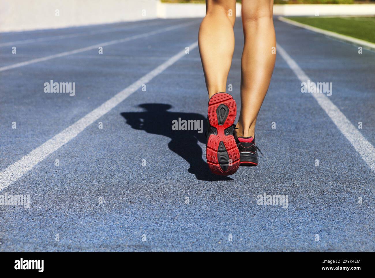 Athlete runner feet down stadium track. Closeup on female shoe and legs ...