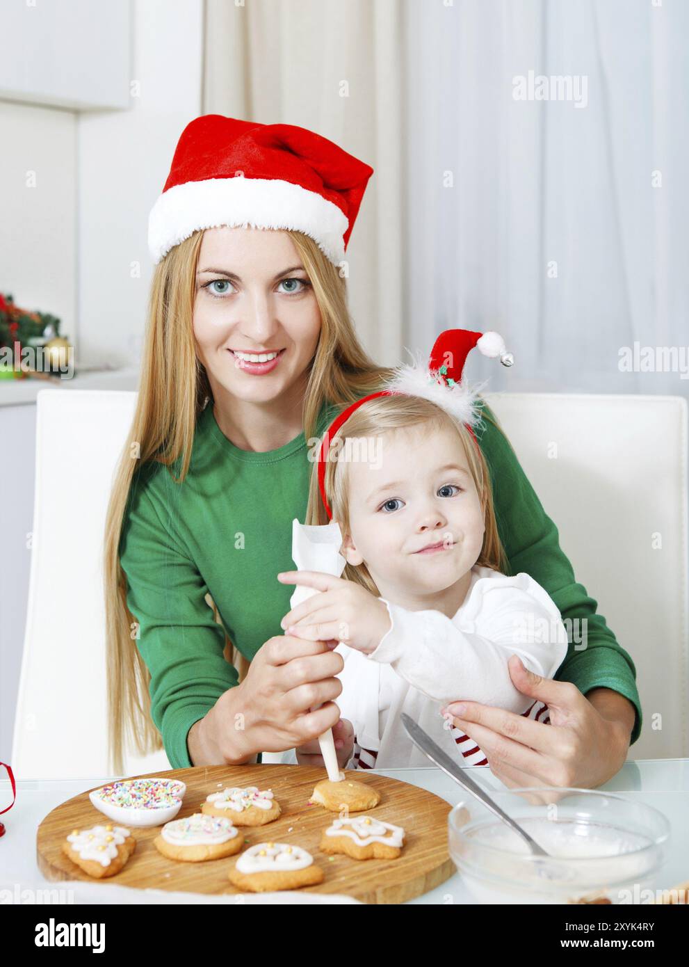 Adorable little girl with her mother baking Christmas cookies at the ...