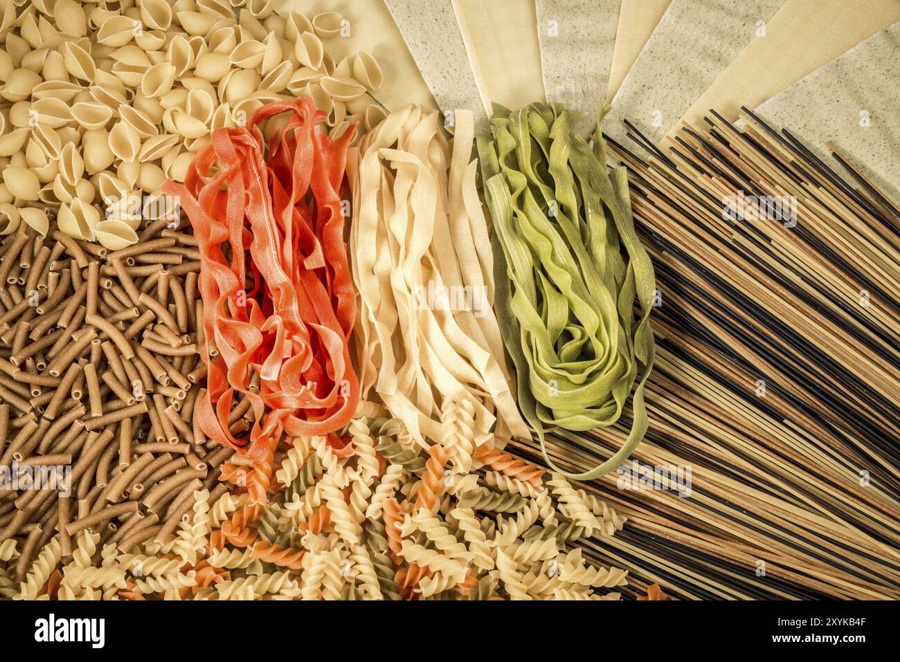 Different kinds of pasta spread over the table with the colours of the ...