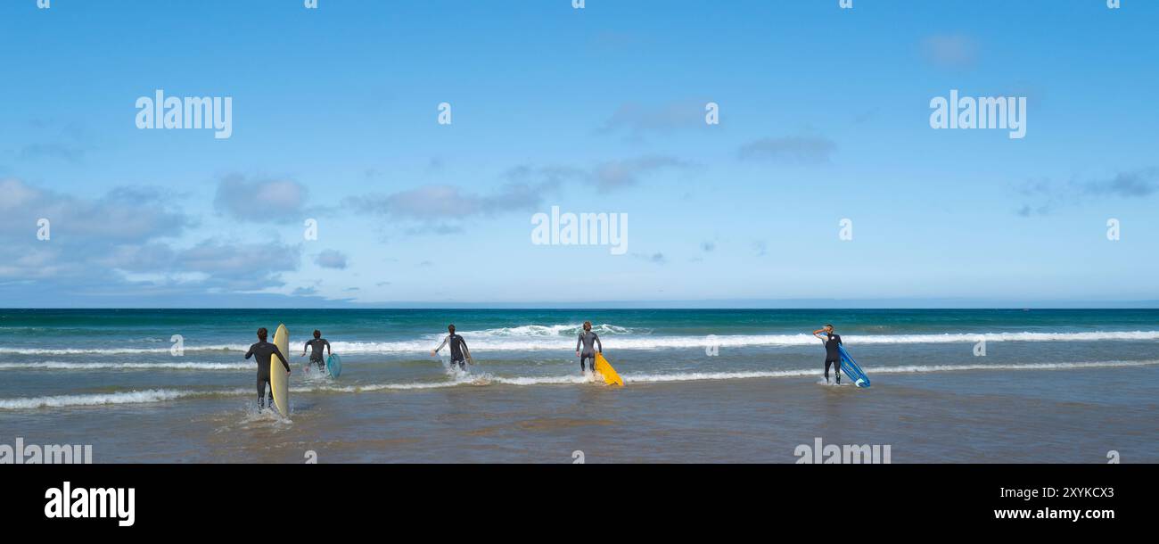 A panoramic image of enthusiastic keen surfers running into the sea at ...