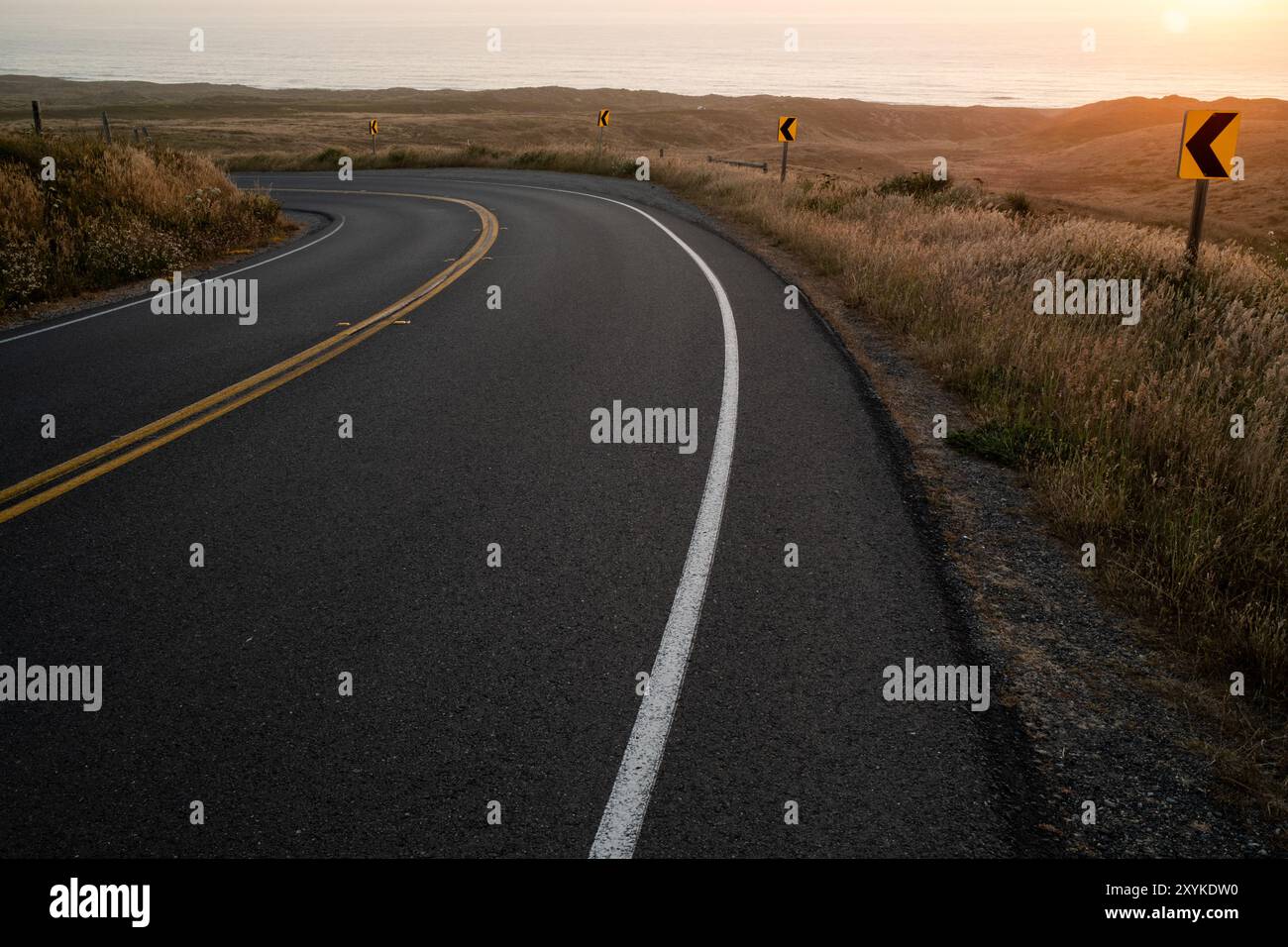 Curving roadway wrapping around hills on the coast during sunset Stock ...