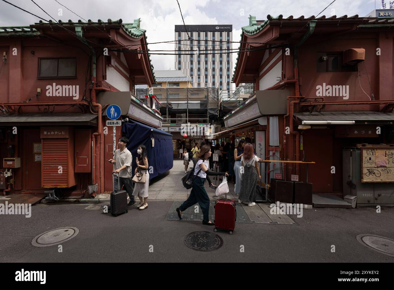Tokyo, Japan. 29th Aug, 2024. Tourists walk with their trolleys behind ...