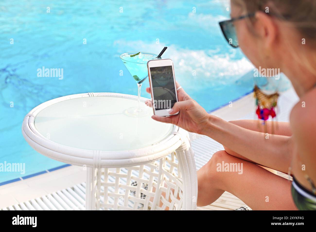 Woman making photo of exotic alcohol cocktail on white table on ...