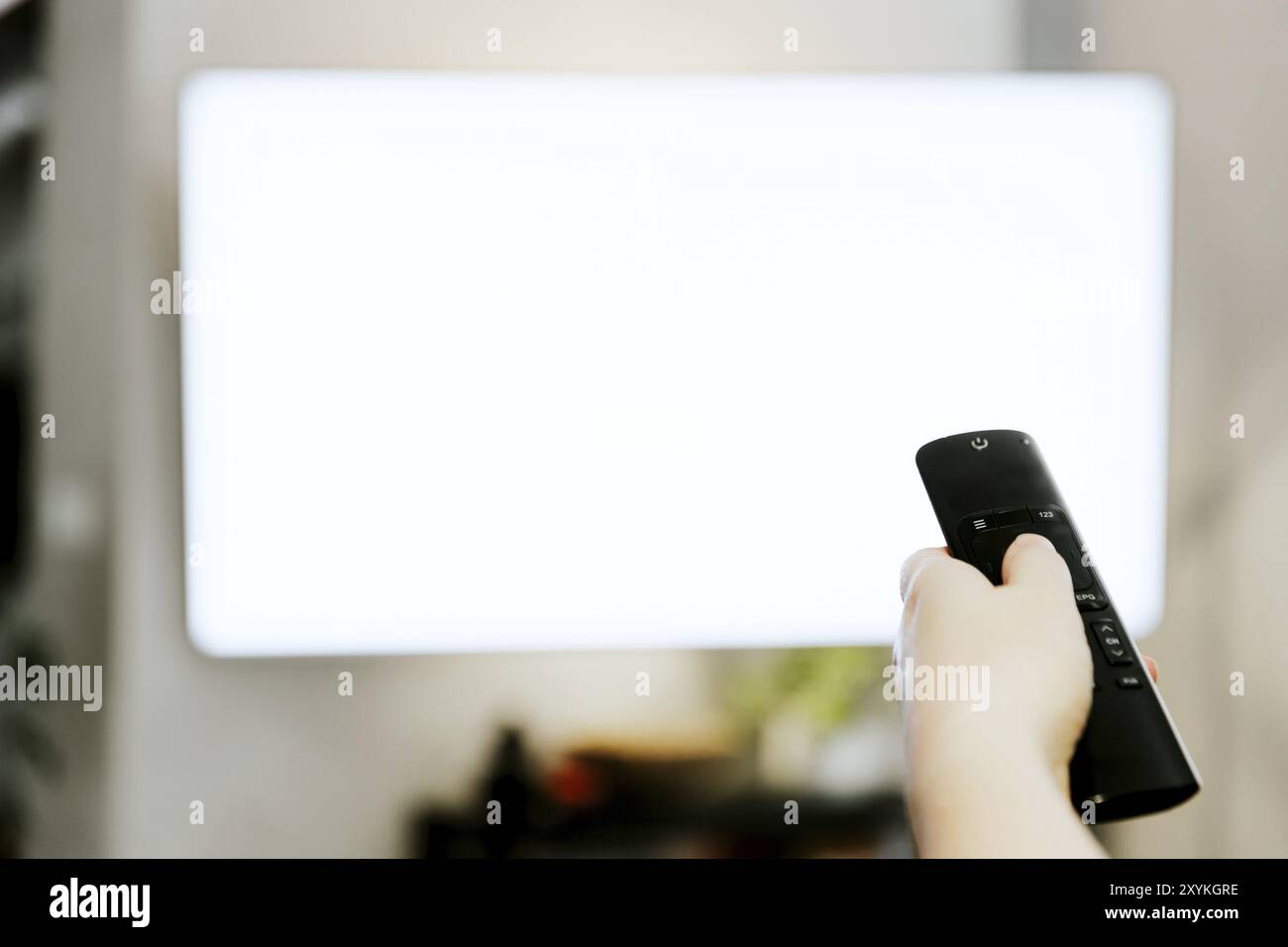 Hand holding remote control pointing to TV. Person watching smart ...