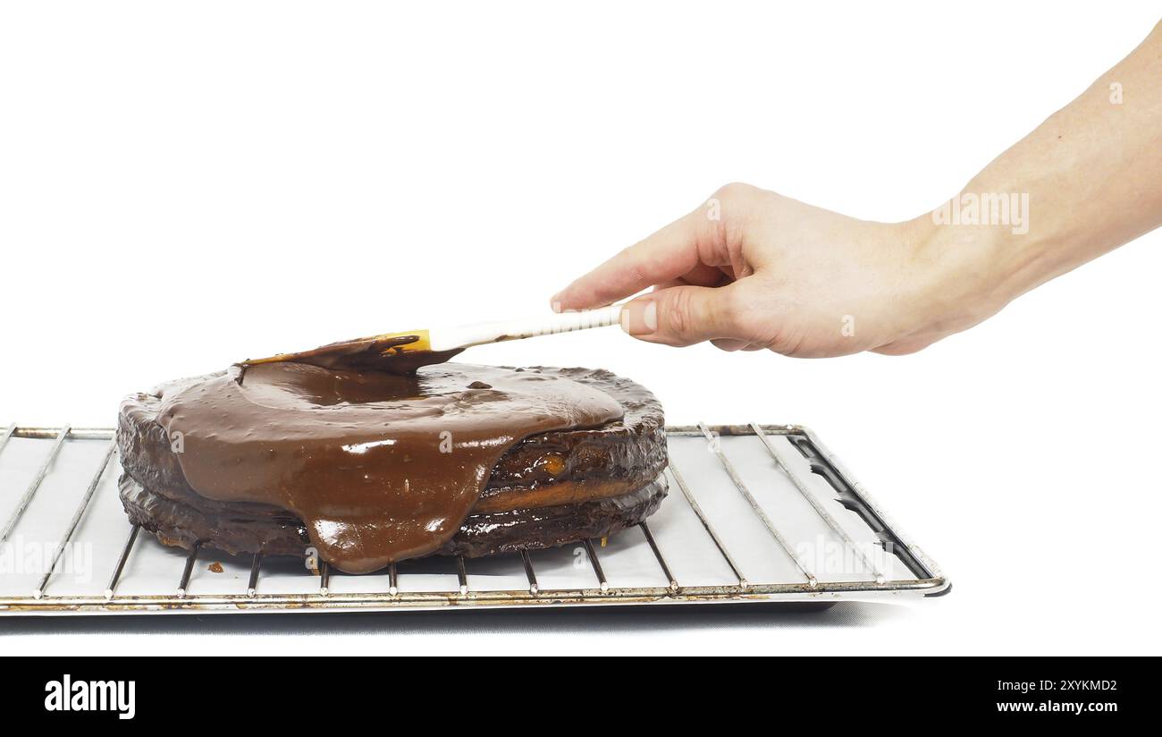 Pastry chef making final touches to a sacher chocolate cake with icing ...