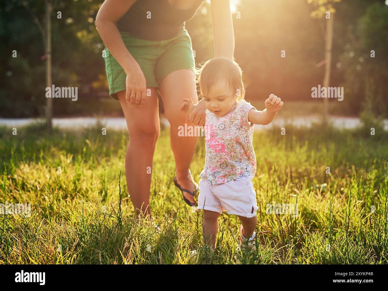 Girl, baby and learning to walk on grass with progress, support or ...