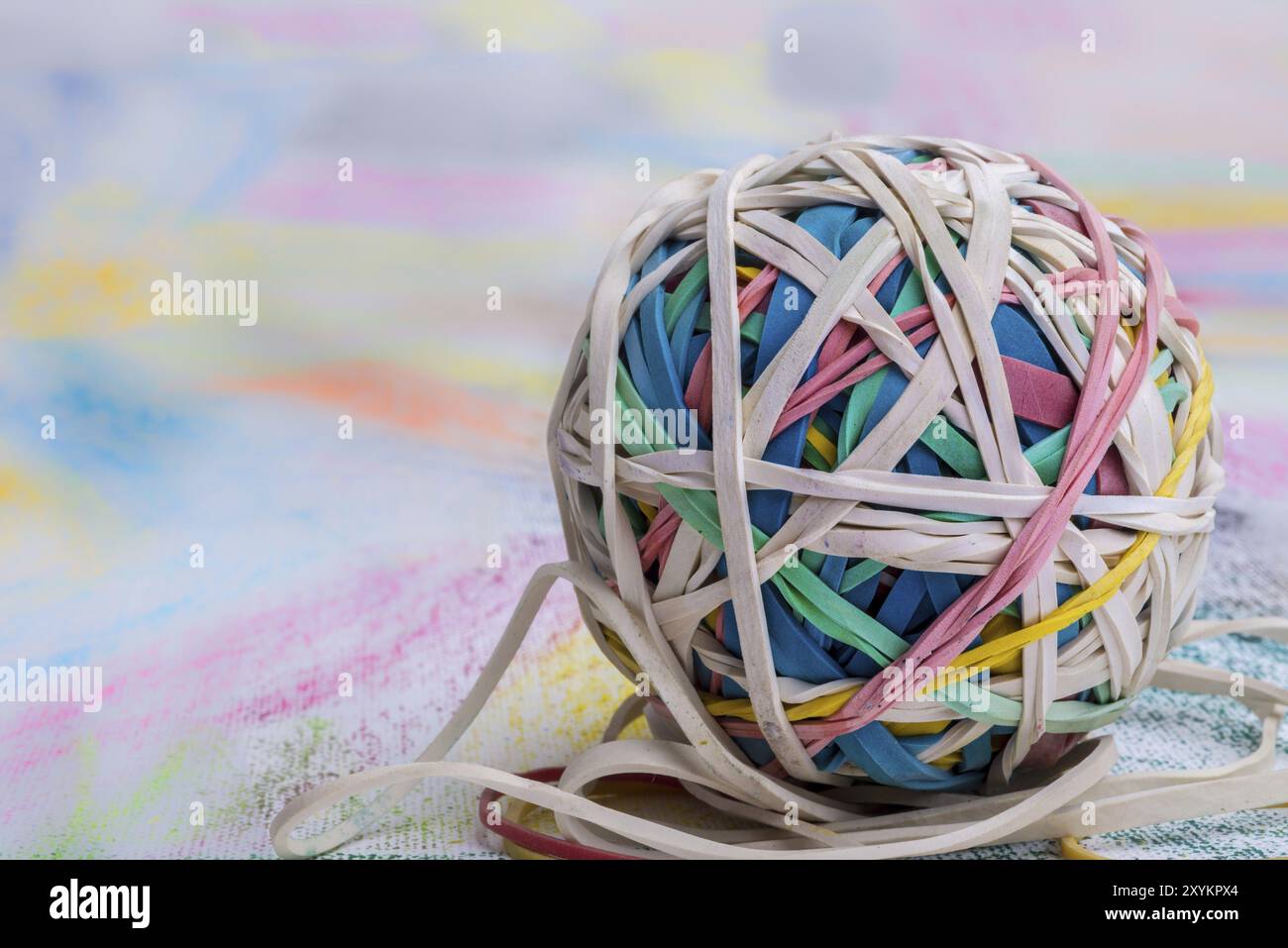 A ball of elastic bands of many different colours placed on a piece of ...