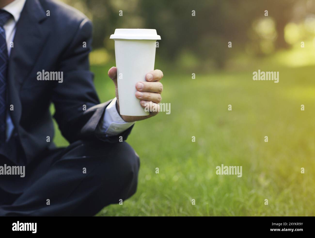 Business man relaxing in a park drinking black coffee in the lotus ...