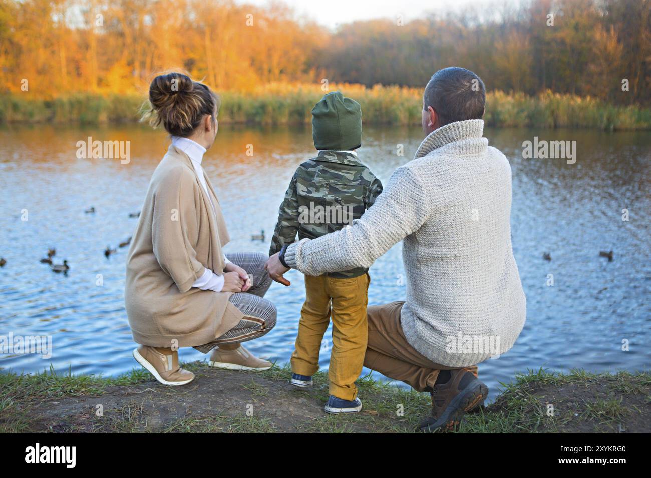 Father, mother and little son feeding ducks by the lake at autumn Stock ...