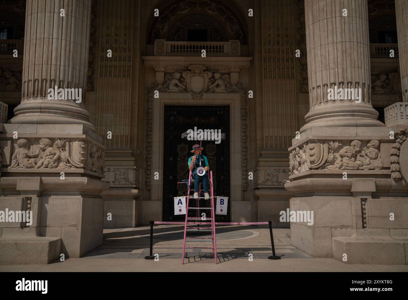 An olympic staff member directs spectators at the start of a fencing ...