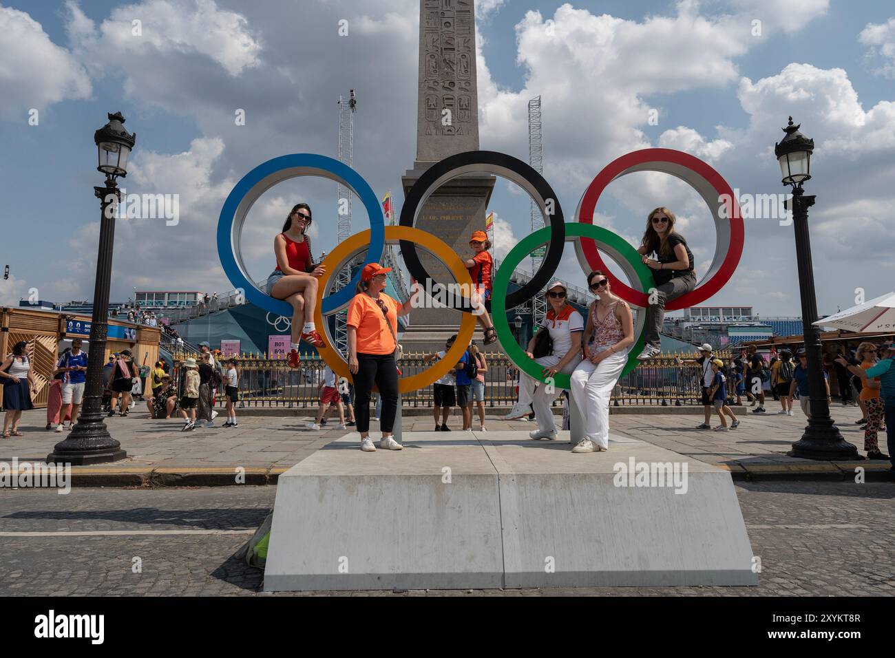 Specators pose for a photograph inside the olympic rings in Place de la ...