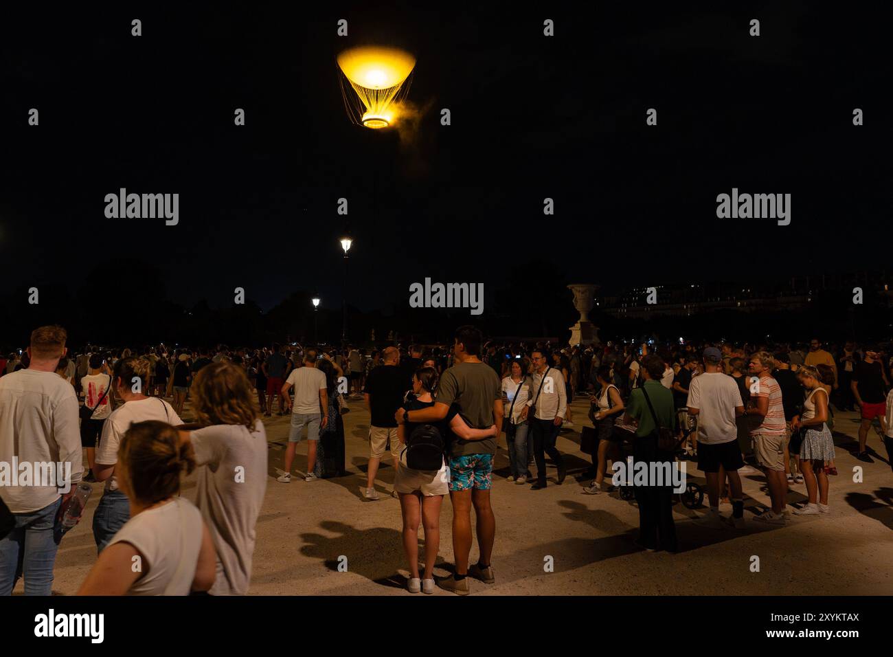 Onlookers watch the Olympic cauldron rise above the French capital in a ...