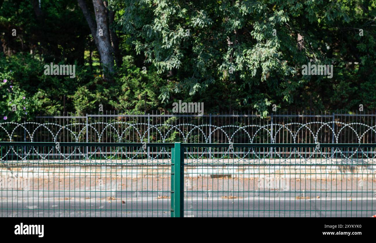 Barbed wire fence barrier in front of trees Stock Photo - Alamy