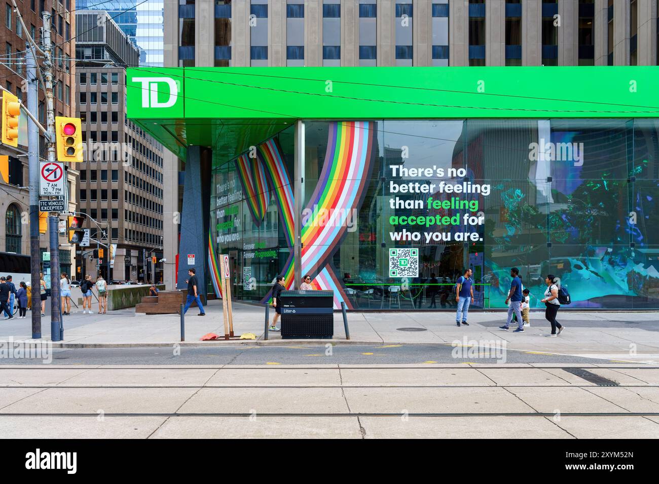 People walking by a TD Bank branch building with LGBTQIA+ decorations ...