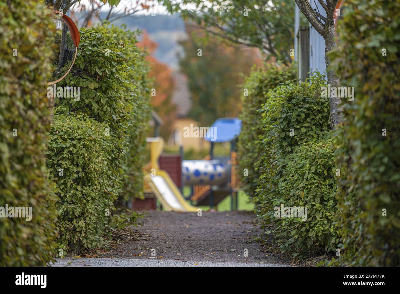 Colorful playground at the end of a walking path between hedges Stock ...