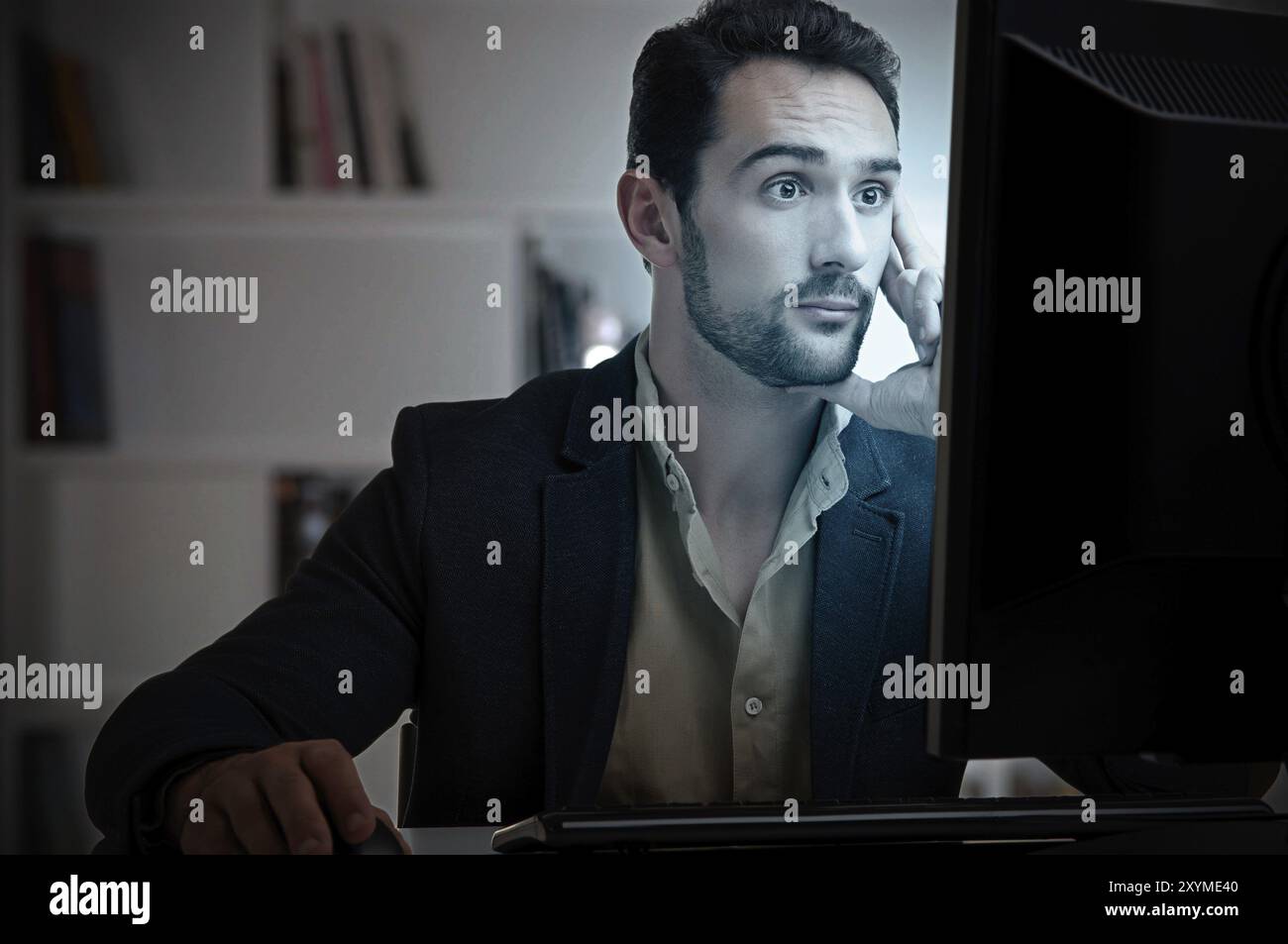 Surprised man looking at a computer screen, in a dark room Stock Photo ...