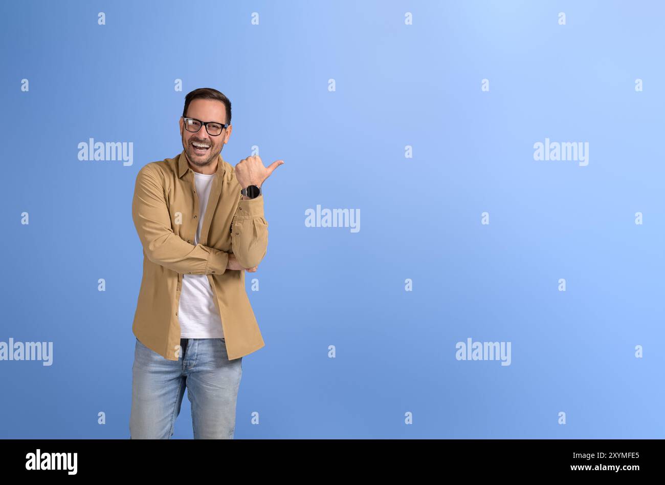 Cheerful young salesman pointing at copy space and demonstrating new ...