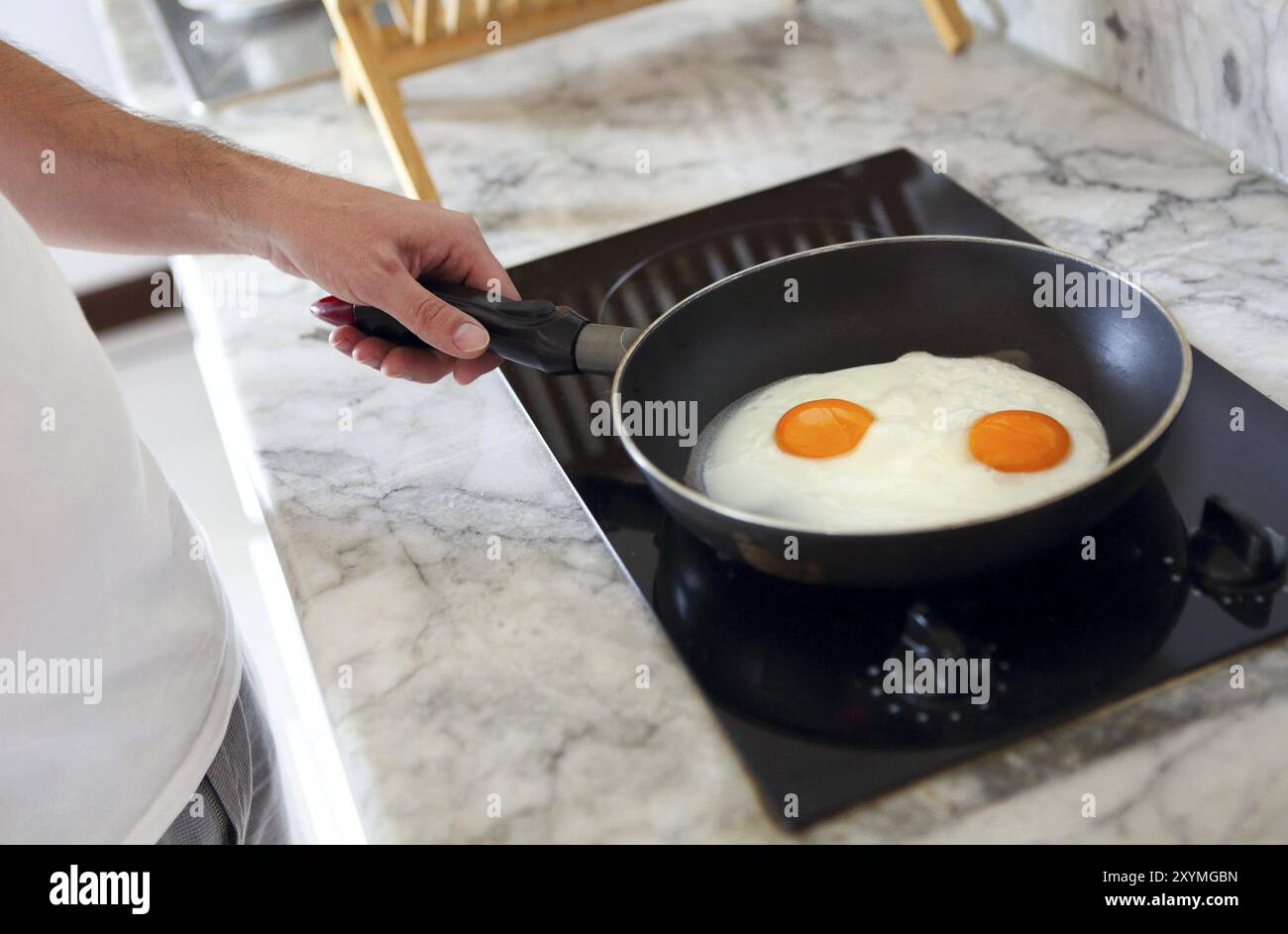 Young man cooking eggs hi-res stock photography and images - Alamy