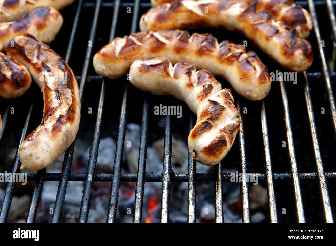 Delicious grilled sausage on a barbecue grill. Underneath charcoal and ...