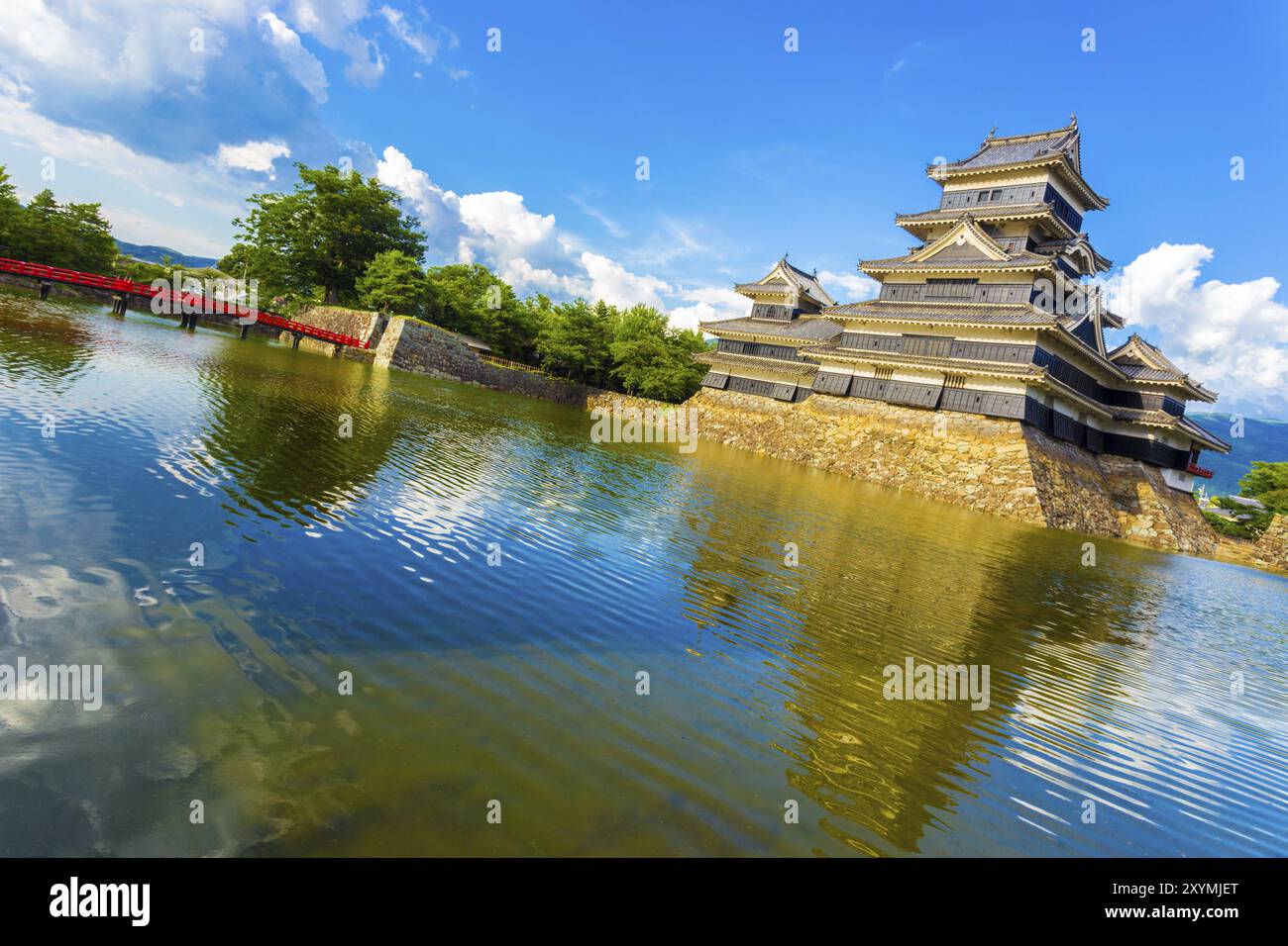 Tilted view of Matsumoto Castle, red bridge and moat water reflection ...