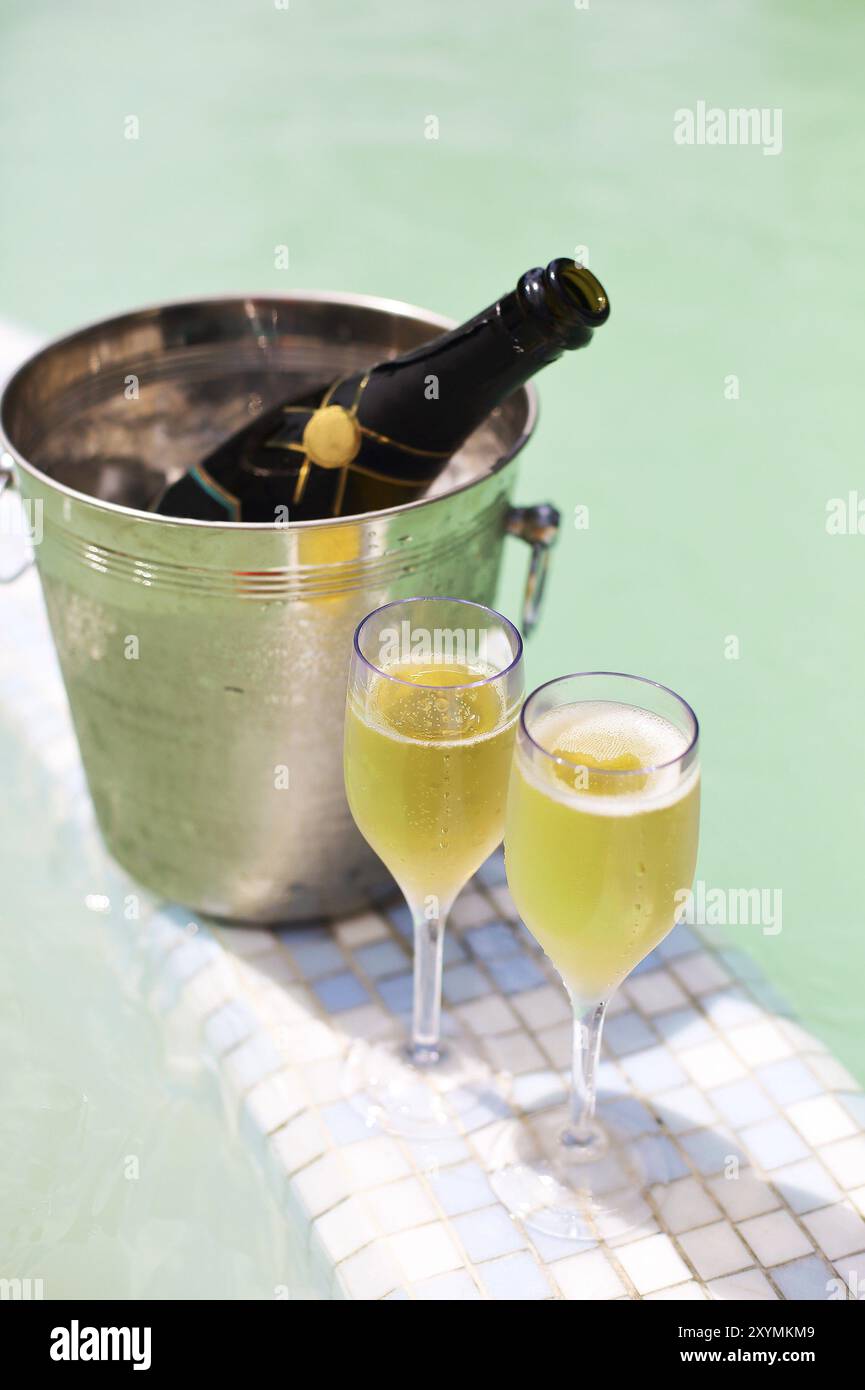 Champagne glasses and bottle in ice bucket near swimming pool. Vacation ...
