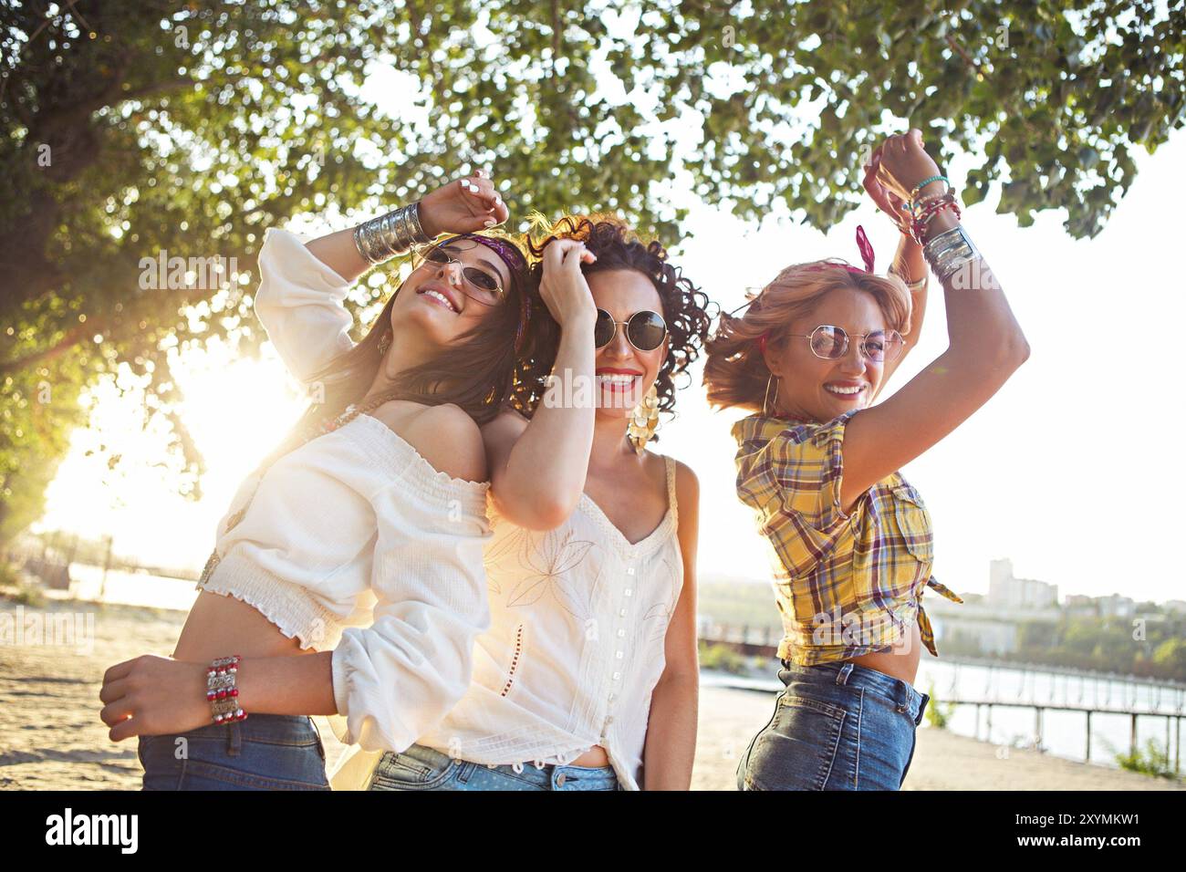 Happy slim tan women are dancing on the beach in sunset. Travel and ...