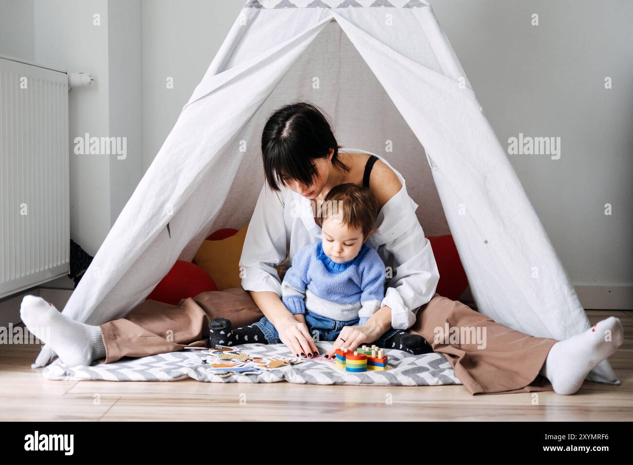 Mother playing with toddler in makeshift indoor tent. Early childhood ...