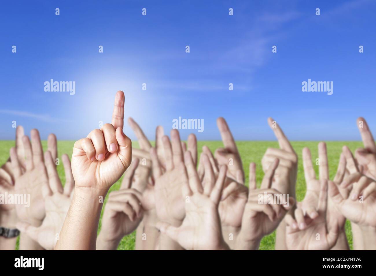 Group of people raising hands to answer a question on a green field ...