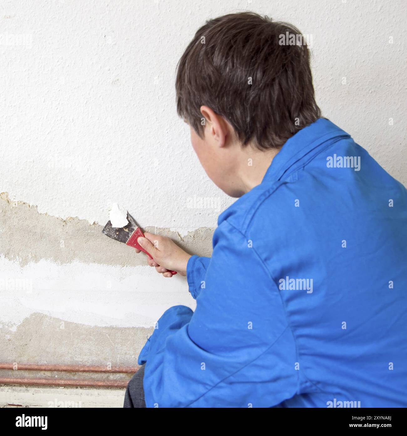 Construction worker removing wallpaper with scraper Stock Photo - Alamy