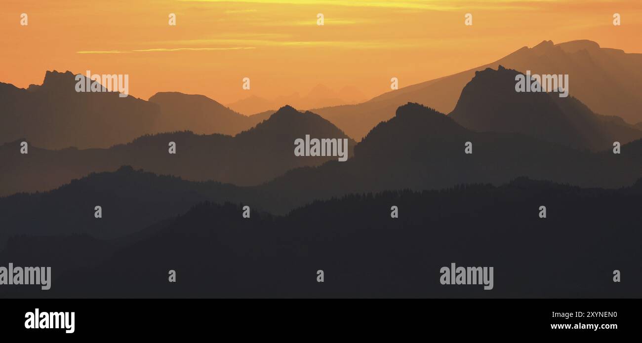 Golden sunrise in the Swiss Alps. Outlines of mountain ranges. View ...