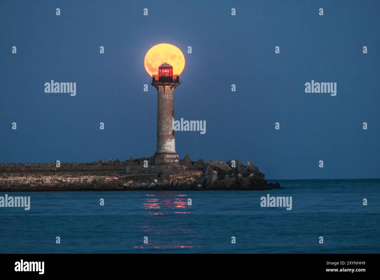 Lighthouse beacon and full moon twilight over sea horizon and moonlight ...