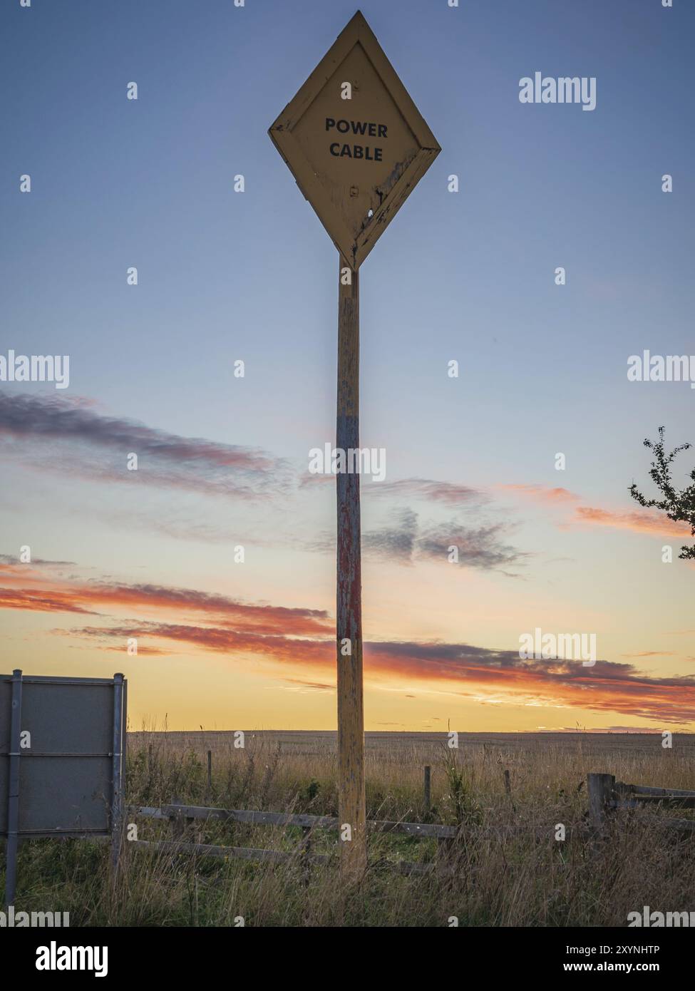 Sign: Power Cable, with evening clouds in the background, seen between ...