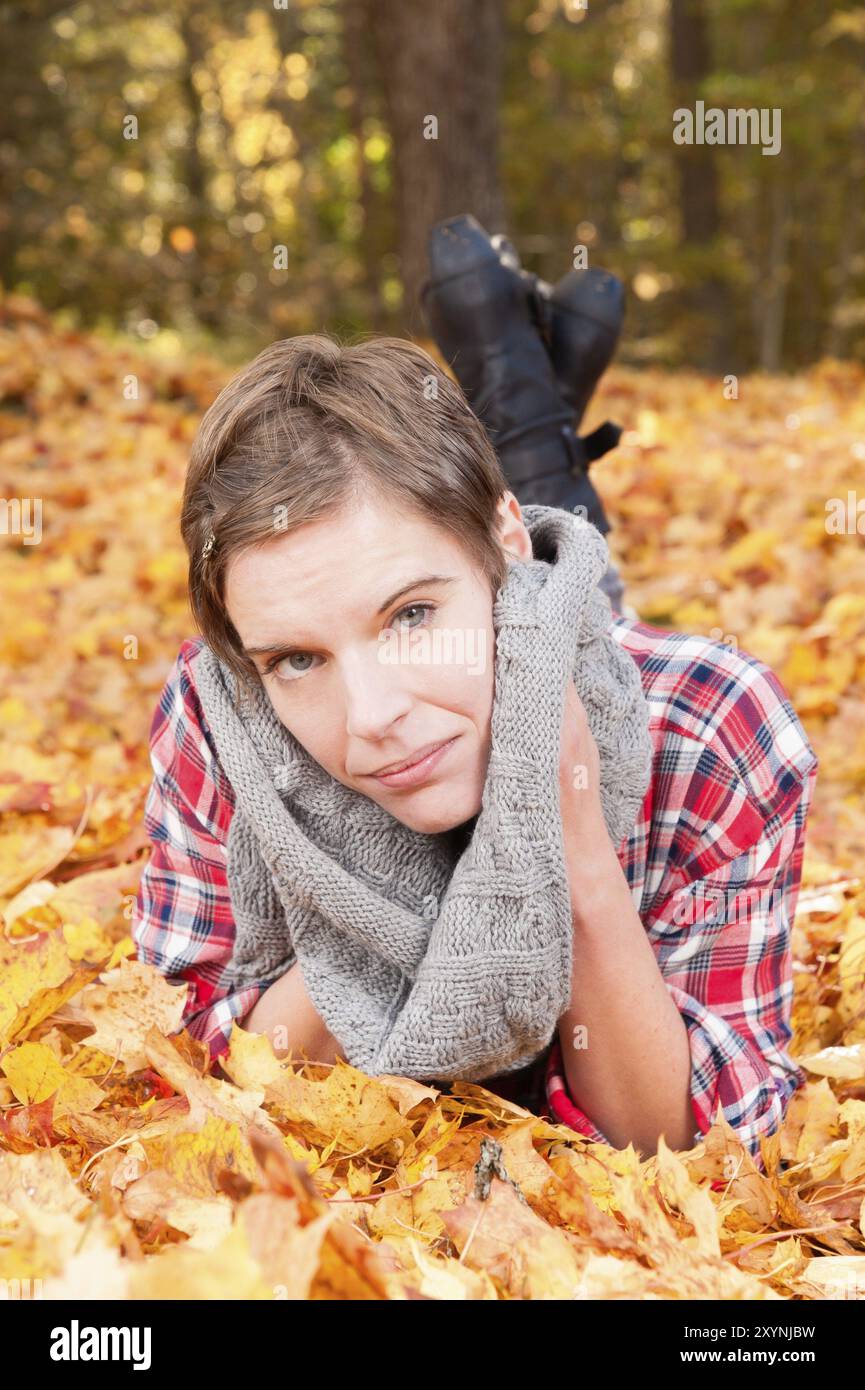 Attractive woman lying on her stomach in the beautiful autumn leaves of ...