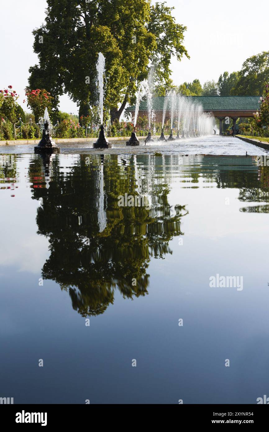 A series of water fountains reflected in a calm central pool of water ...