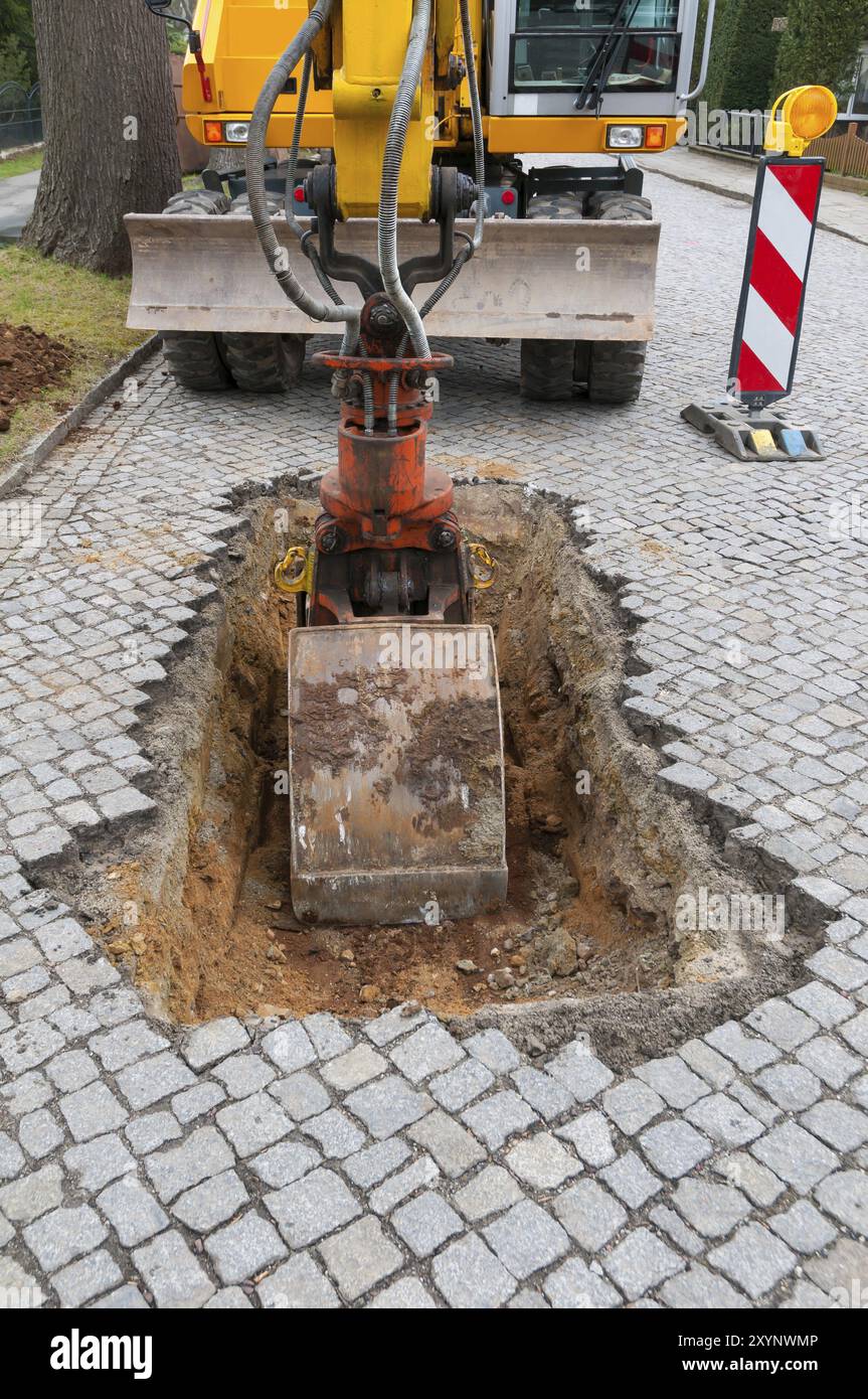 Excavator excavating a building pit in a street. Excavator working on a ...