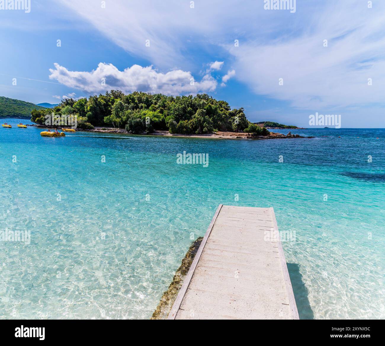 A view along a wooden jetty towards islands offshore from the beach at ...