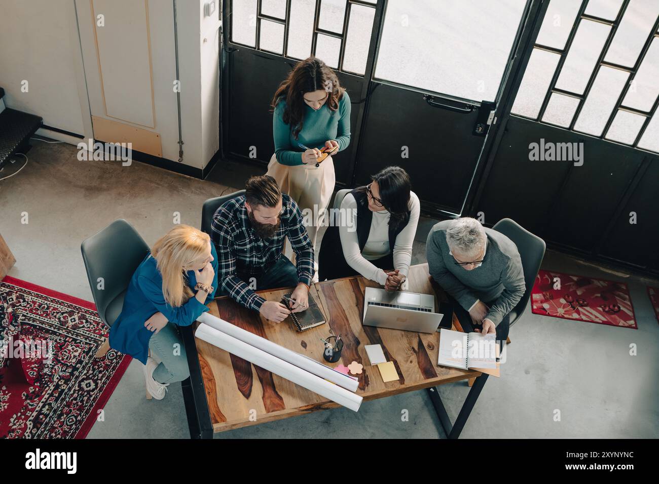 Five business people having a business meeting around a wooden table ...