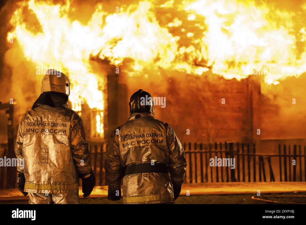 Arson or nature disaster, firefighters at burning fire flame on wooden ...
