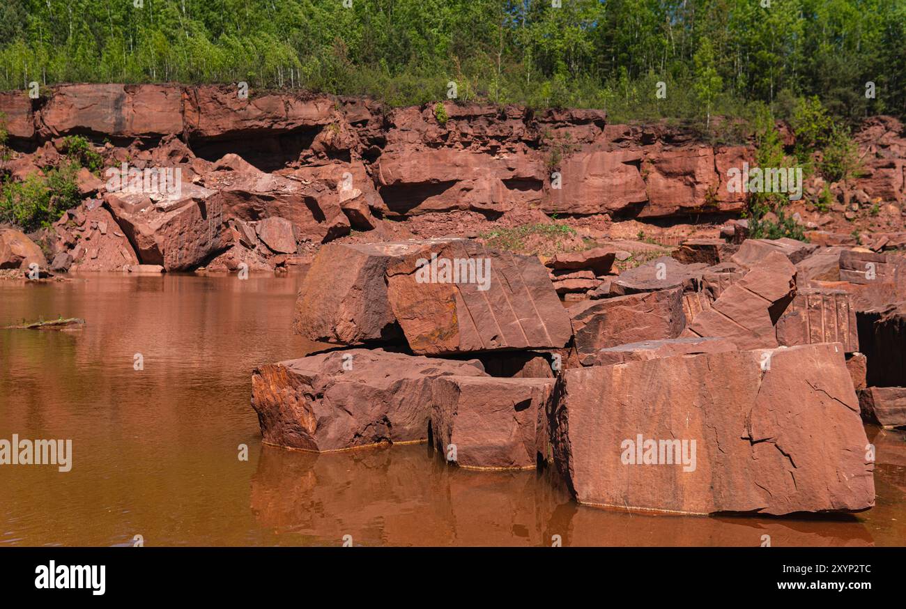 Landscape of an abandoned red sandstone quarry with water filling its ...