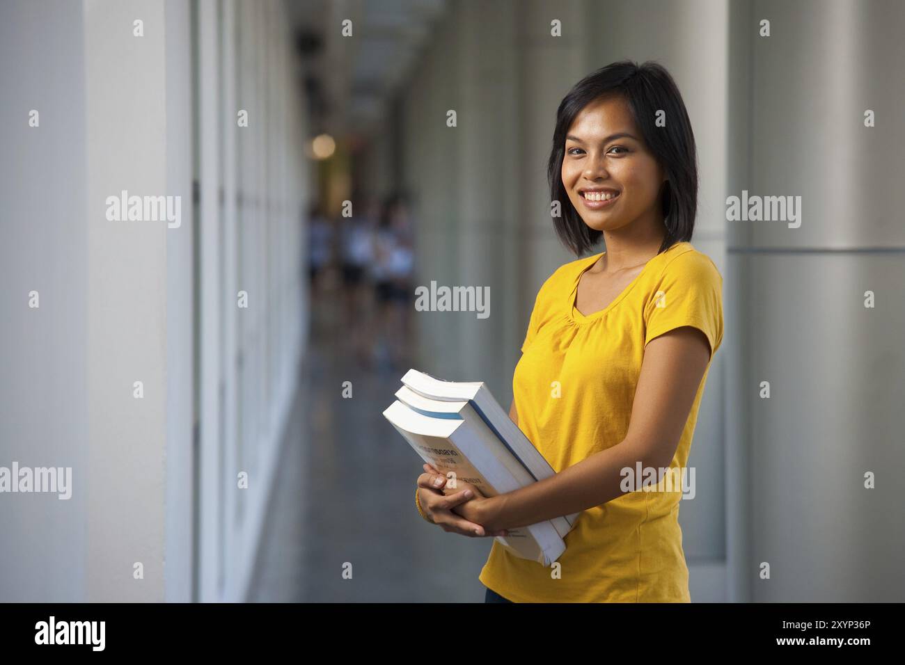Half portrait of an adorable happy college student holding books and ...